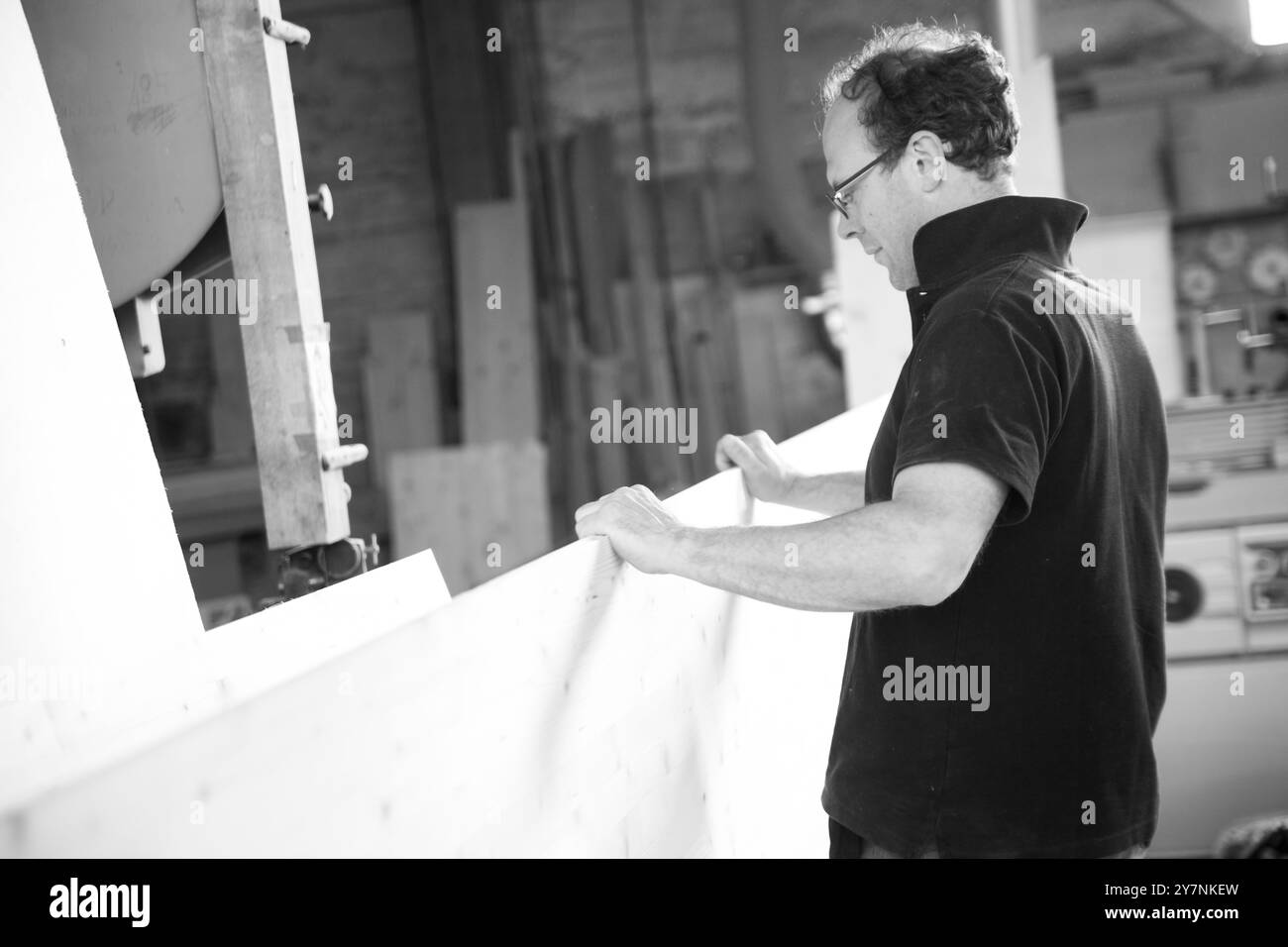 Black and white image of A carpenter is working on a large wood panel ...