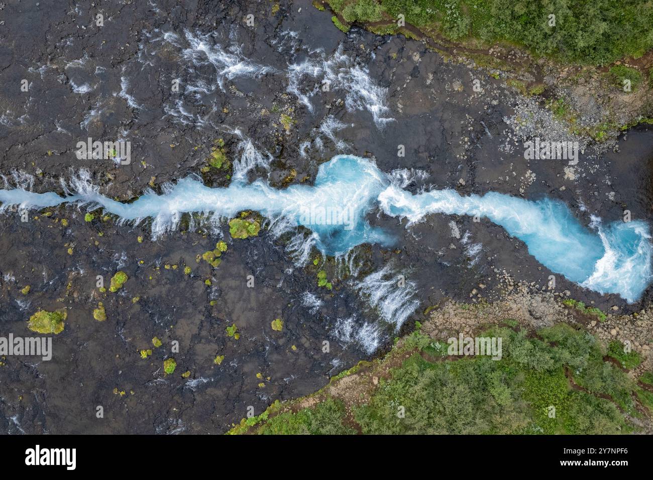 Aerial view of a river with clear blue water flowing through rocky ...