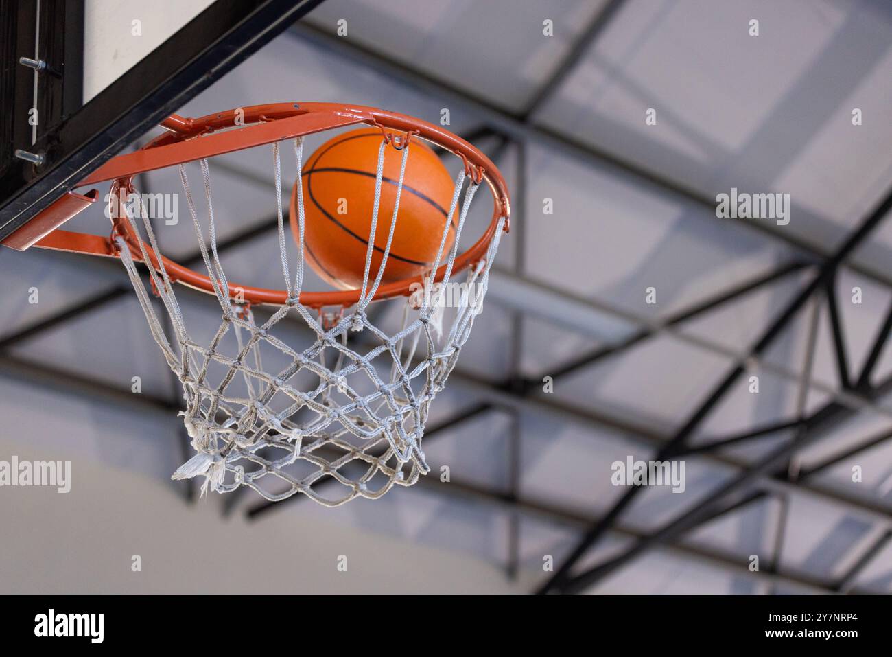Basketball going through hoop in indoor court during game or practice ...