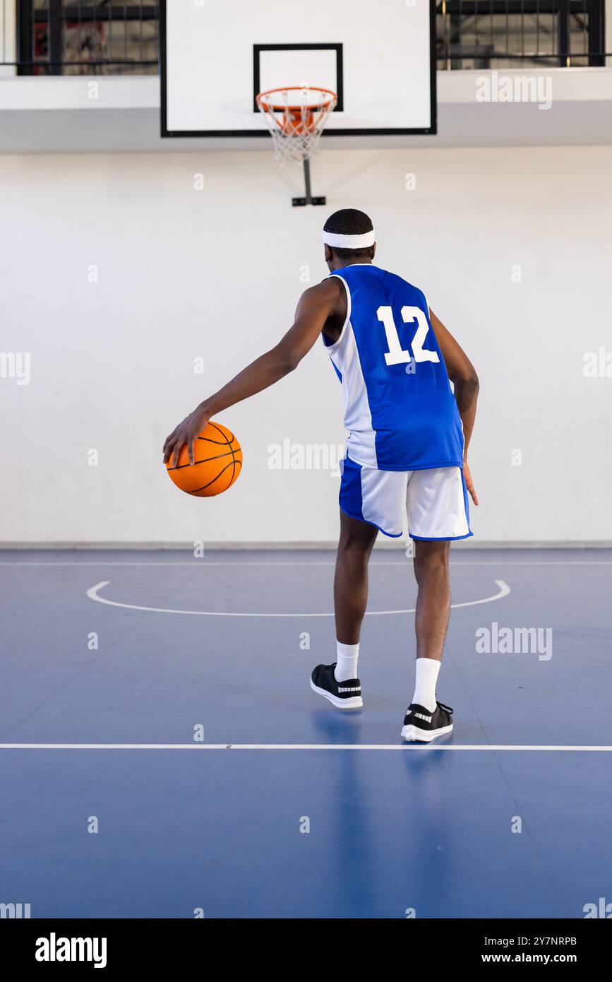 Dribbling basketball on court, player in blue jersey practicing skills ...