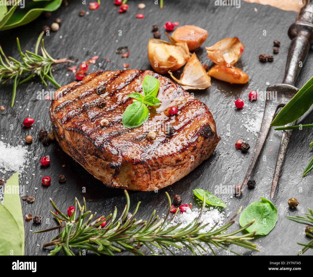 Grilled delicious ribeye steak and some seasonings and herbs on black ...