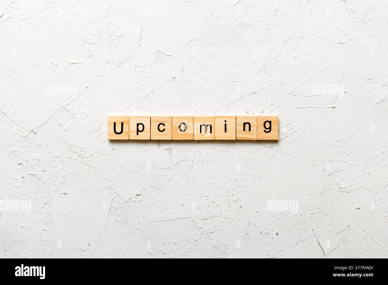 UPCOMING word written on wood block. UPCOMING text on cement table for ...