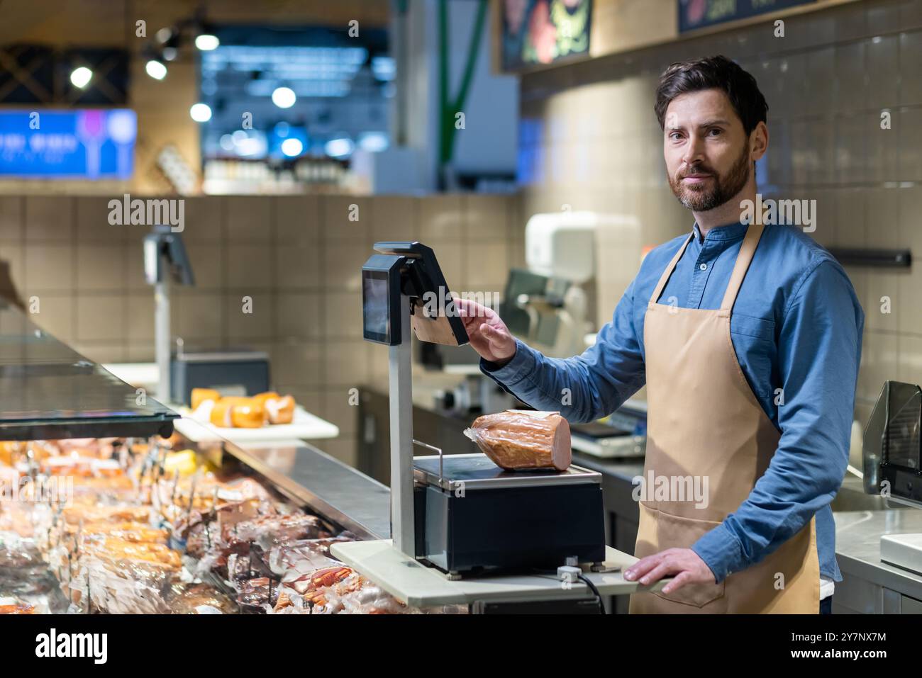 Butcher wearing apron at deli counter in supermarket presenting fresh ...