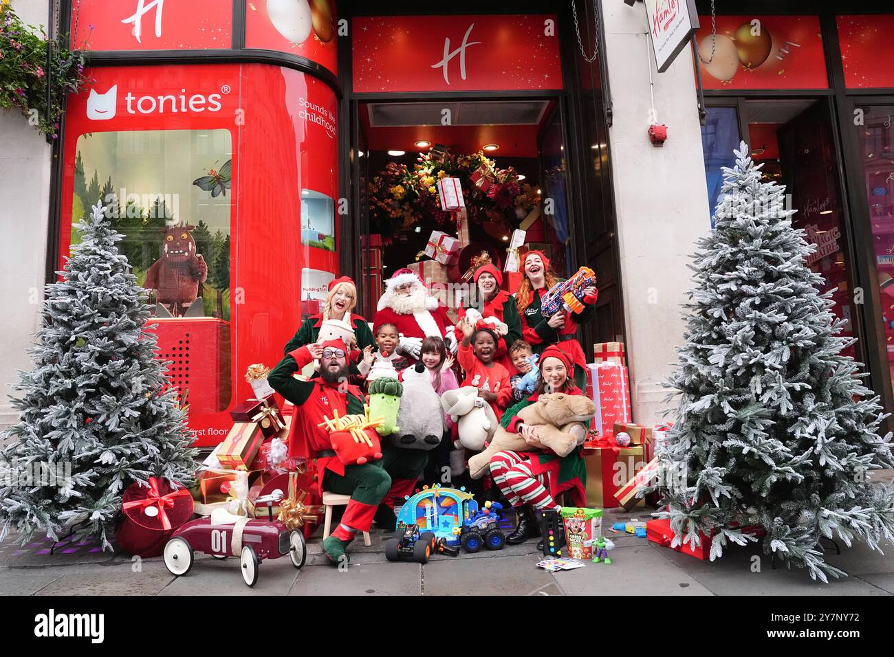 A group of children with Santa and elves pose for a photo outside ...