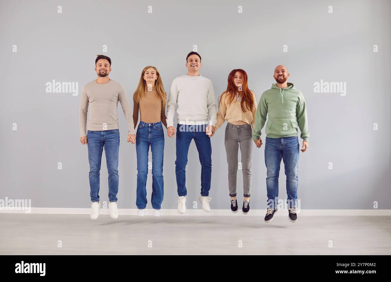 Group portrait of young happy people making jump together hands holding ...