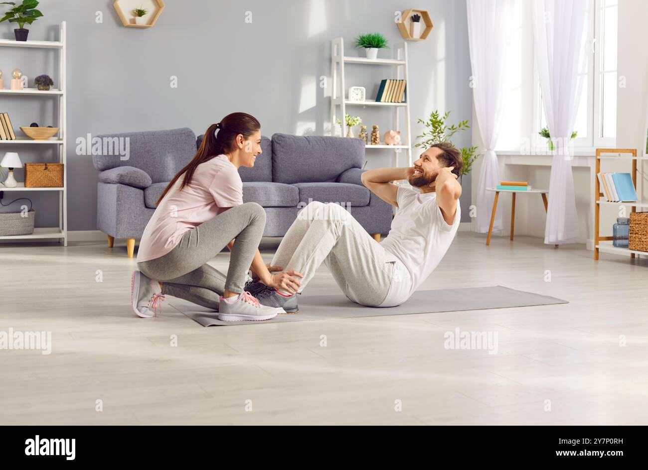 Happy sporty young woman helping her husband doing sport fit exercises at home Stock Photo - Alamy