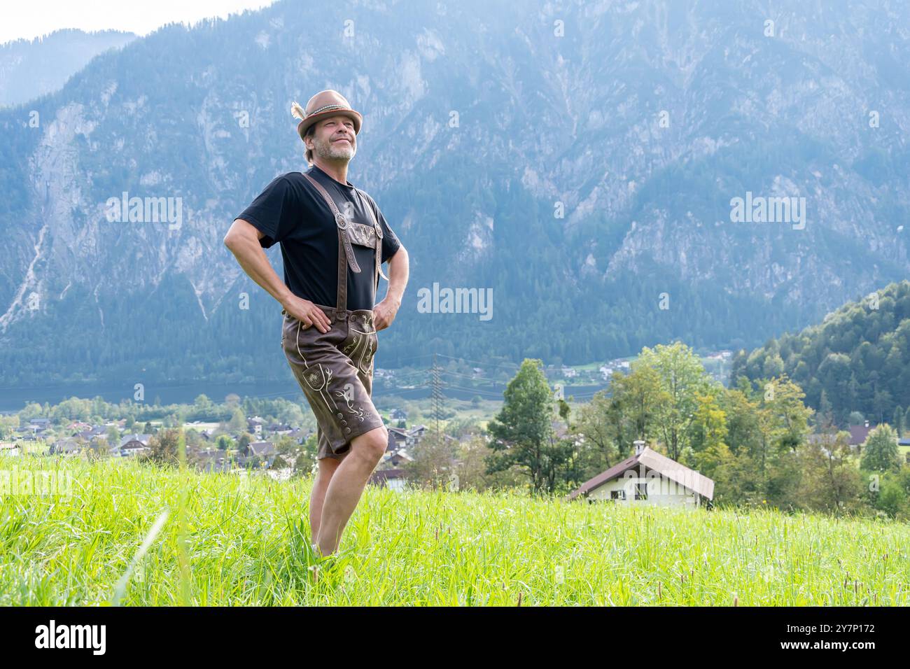 An elderly farmer in Austrian national dress dances against a backdrop ...