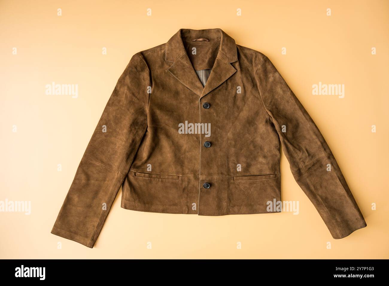 Light brown suede jacket lies on a peach fuzz background. Slow fashion ...