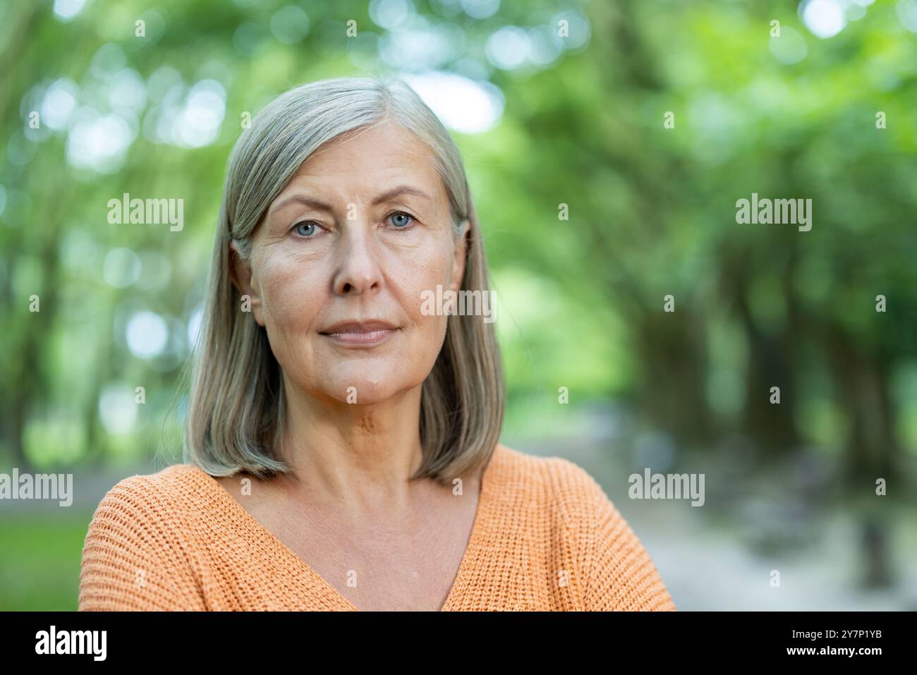 Mature woman with gray hair standing confidently in outdoor setting ...