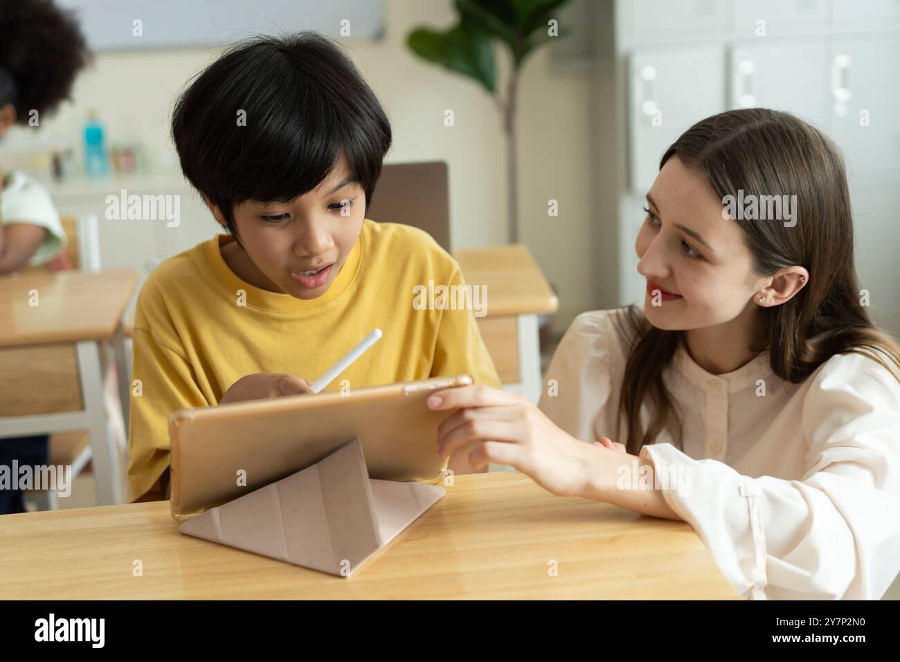 Teacher Guiding Student with Digital Learning in Diverse Classroom Stock Photo - Alamy
