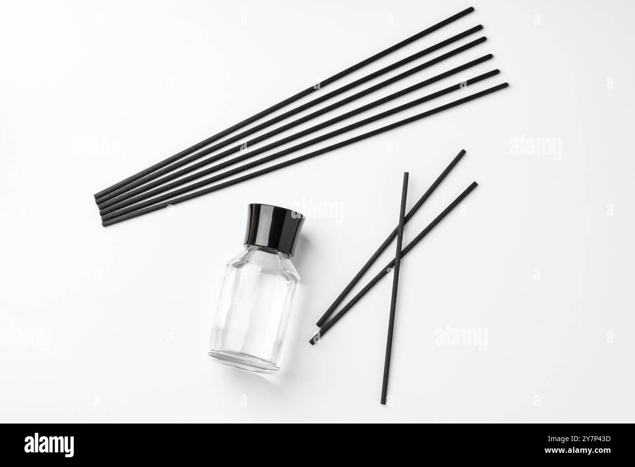 A minimalist display of essential oil and black diffuser sticks on a ...