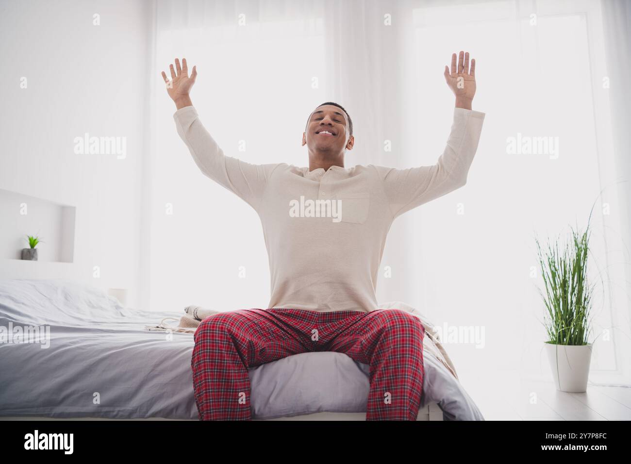 Photo of nice young man sit bed pray salute sun wear pajama enjoy wake ...