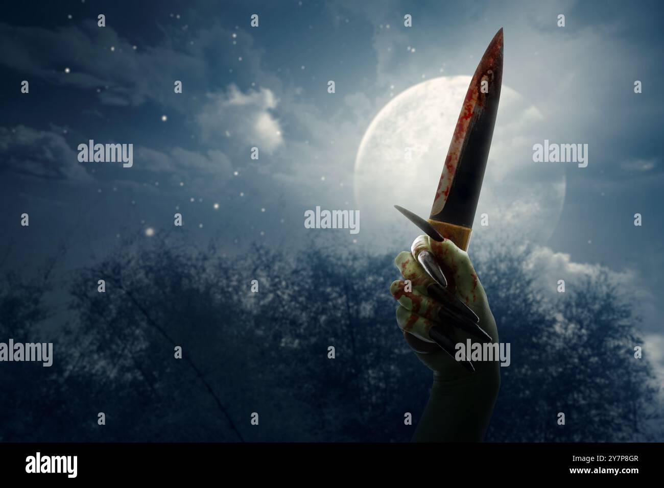 Witch hand with long black nail holding knife in a dark forest with ...