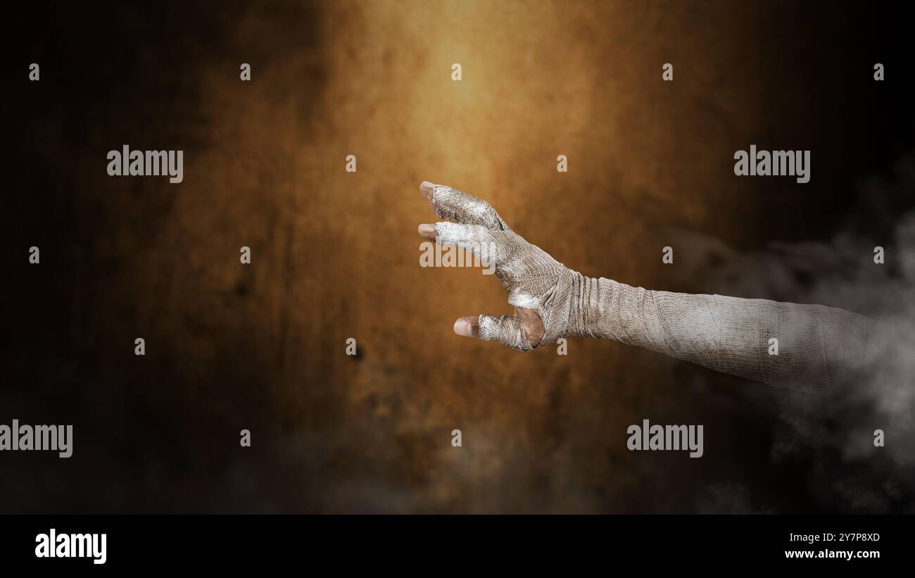 Mummy hand in bandages rising out of fog with a dark background. Scene ...