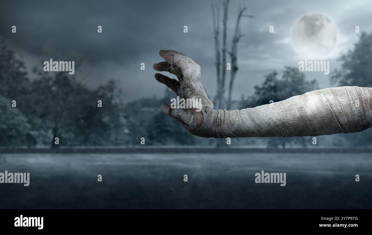 Mummy hand in bandages rising out with full moon background. Scene has ...