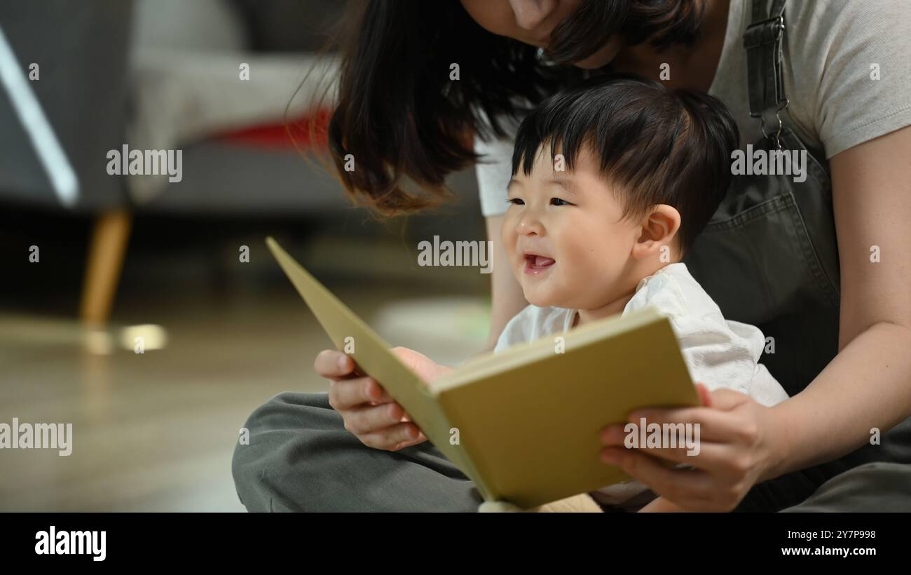 Mother reading book to her adorable toddler son on floor in living room ...