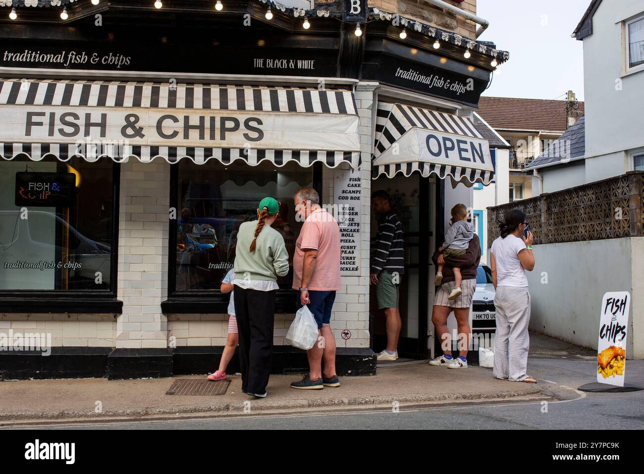 People queue outside a traditional fish and chip shop in Combe Martin ...