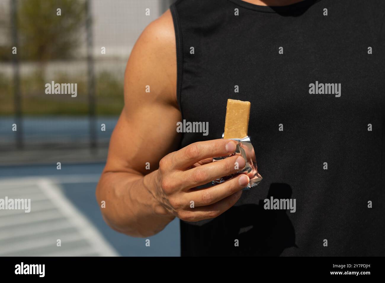 Sports man eating energy bar. Muscular athlete snacks on protein bar ...