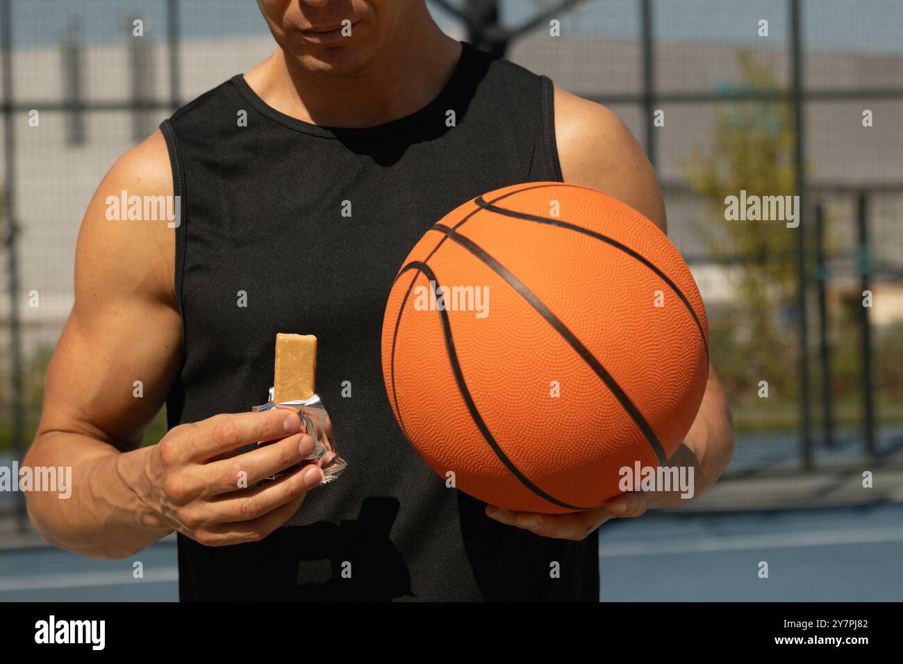 Sports man or basketball player eating energy bar. Muscular athlete ...