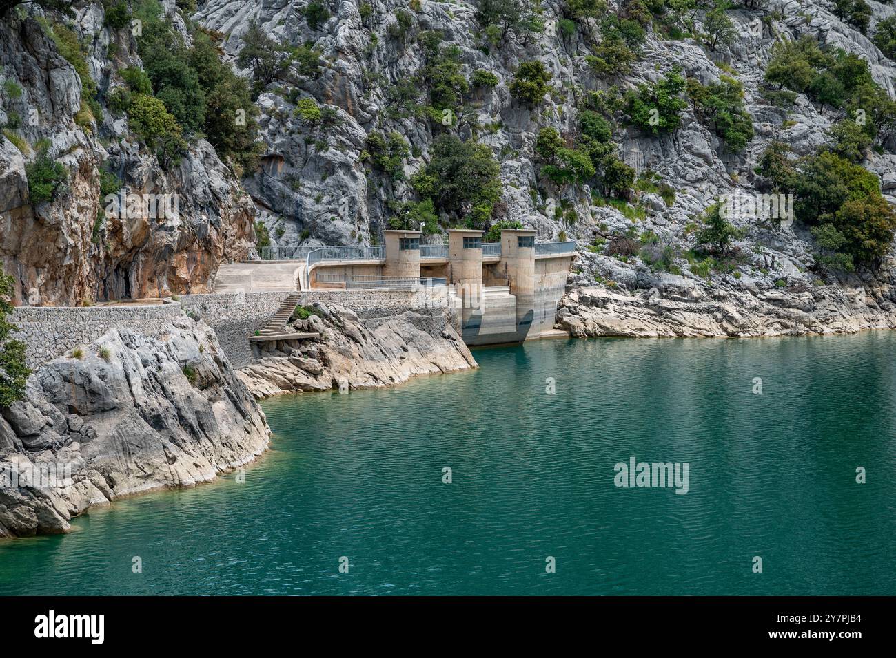 A beautiful dam structure set against rocky cliffs and a clear ...
