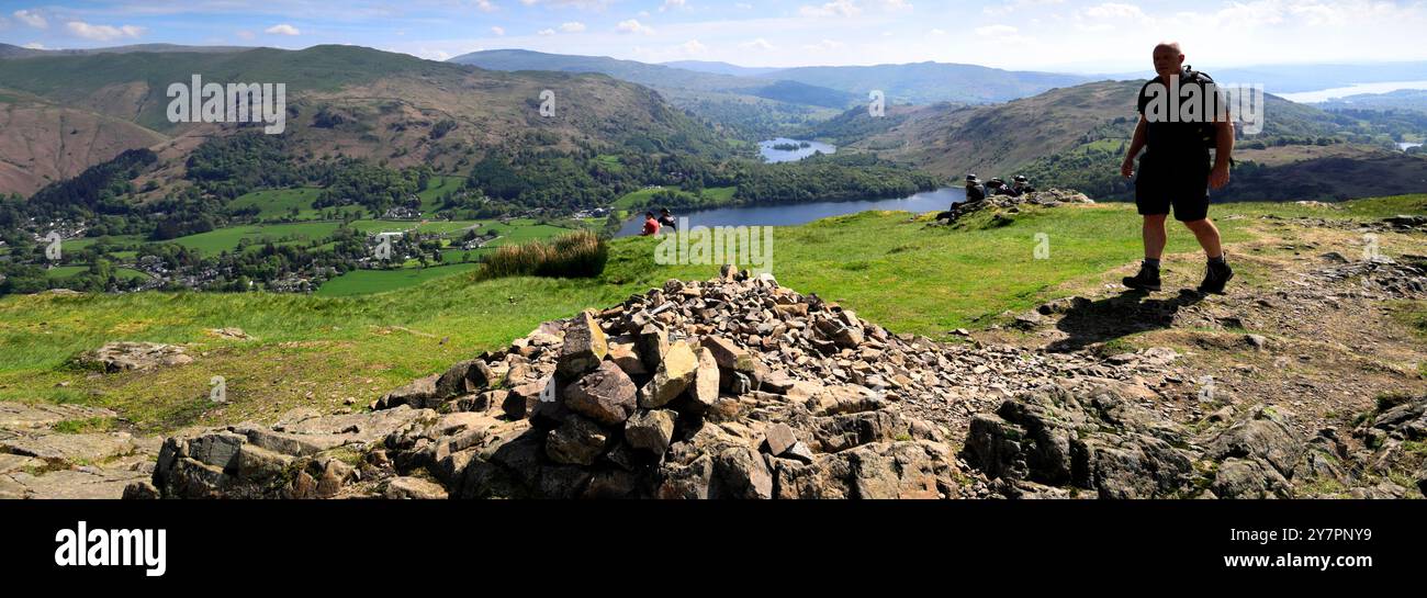 Walker at the summit of Silver Howe fell, above the village of Grasmere ...