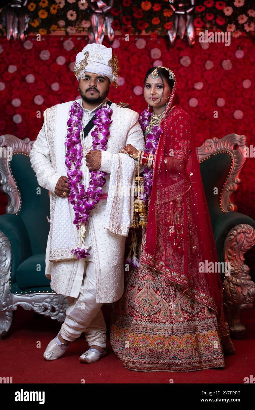 An Indian bride and groom in traditional wedding attire posing for a ...