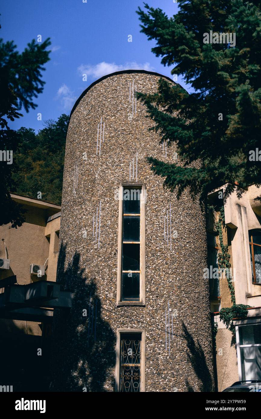A vertical view of a unique cylindrical building with a pebble exterior ...