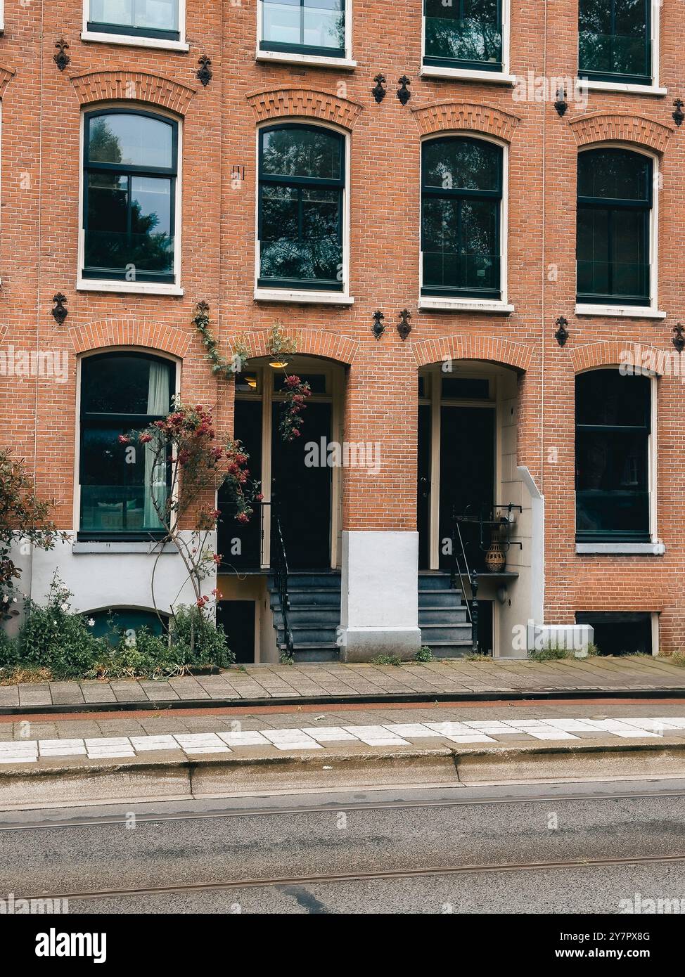 A traditional brick building with large windows and a small garden in ...