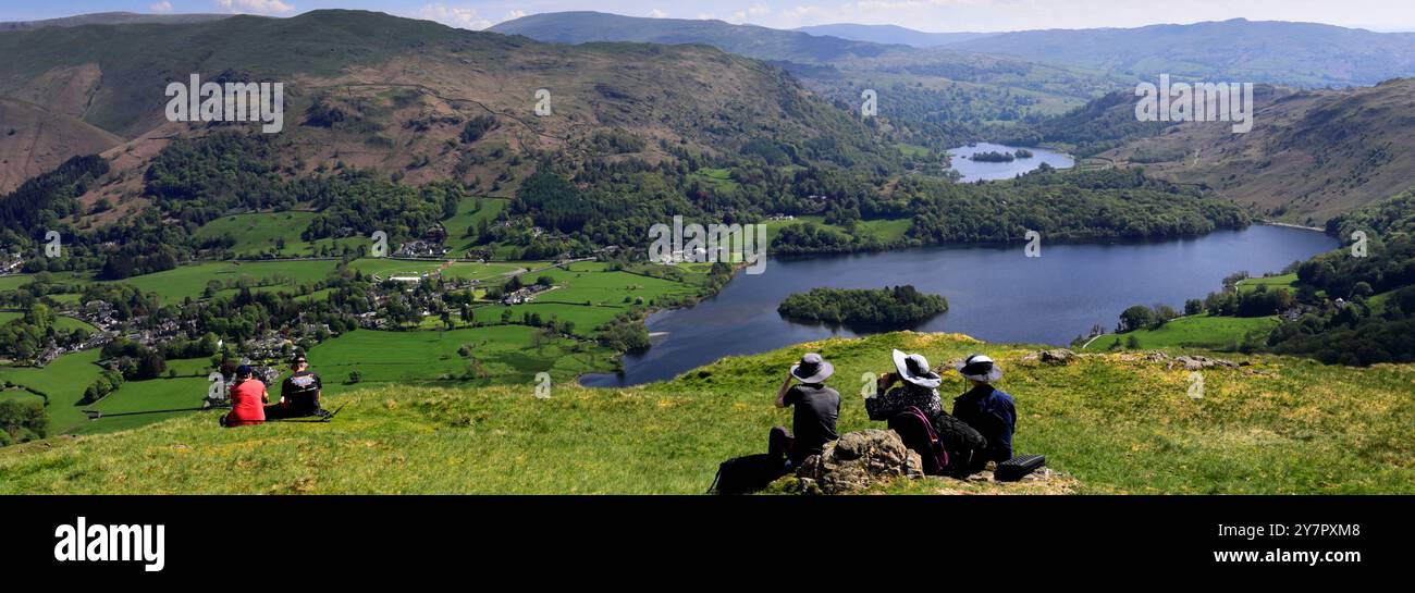 Walker at the summit of Silver Howe fell, above the village of Grasmere ...
