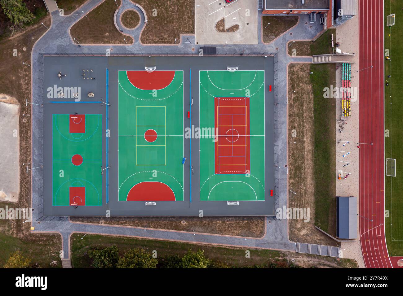 Overhead perspective of vibrant basketball courts and a track at dusk ...
