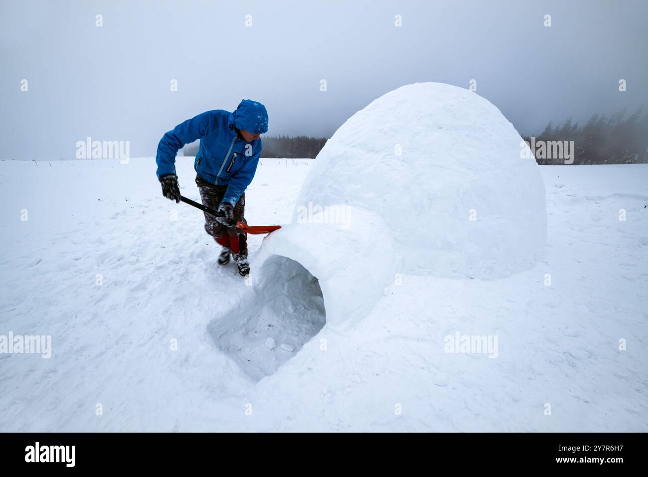 Igloo building in the high mountain. Tourist with snow shovel build ...