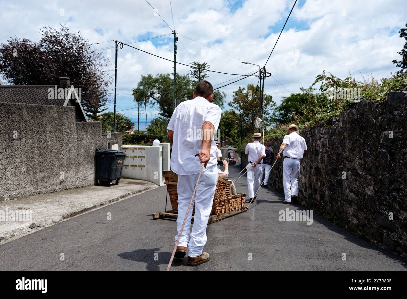 Carreiros walking with wicker sledges in tow under a bright cloudy sky ...