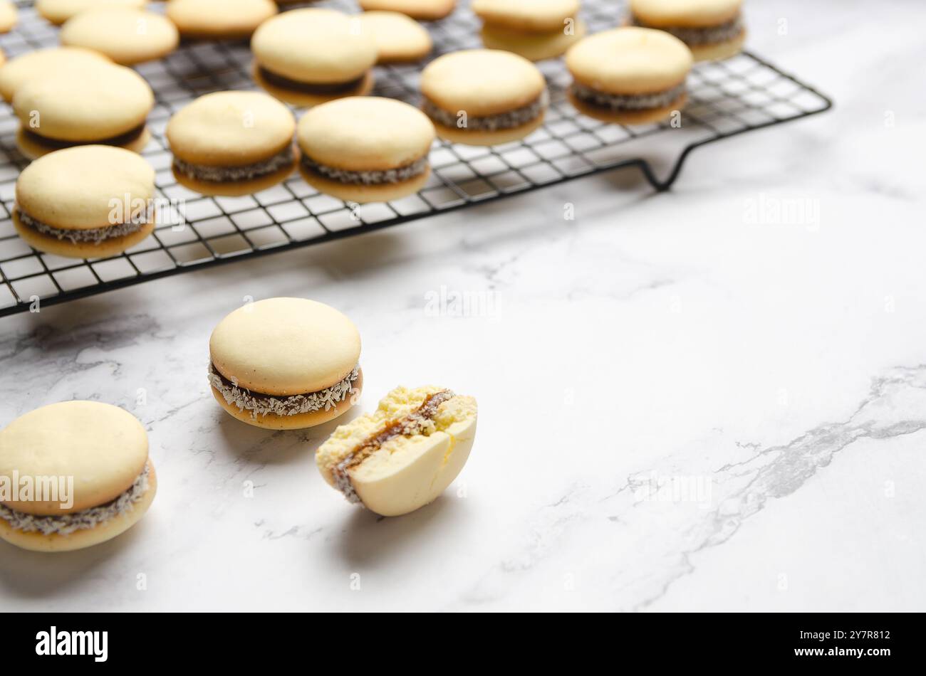 Cornstarch alfajores filled with dulce de leche on a black rack on a ...