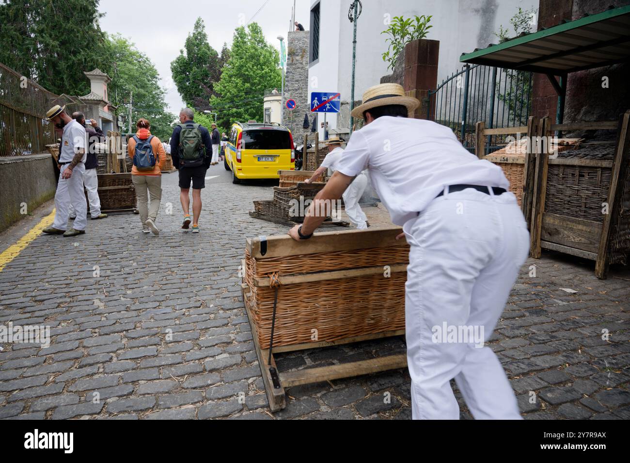 Tourists walk among carreiros arranging wicker sleds for the famous ...