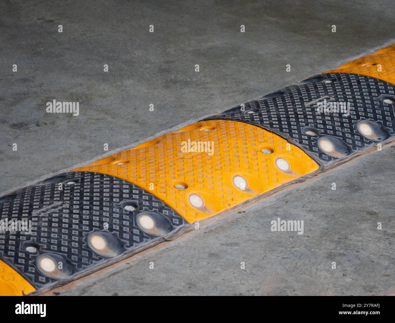 yellow and black traffic safety speed bump on a concrete road at ...