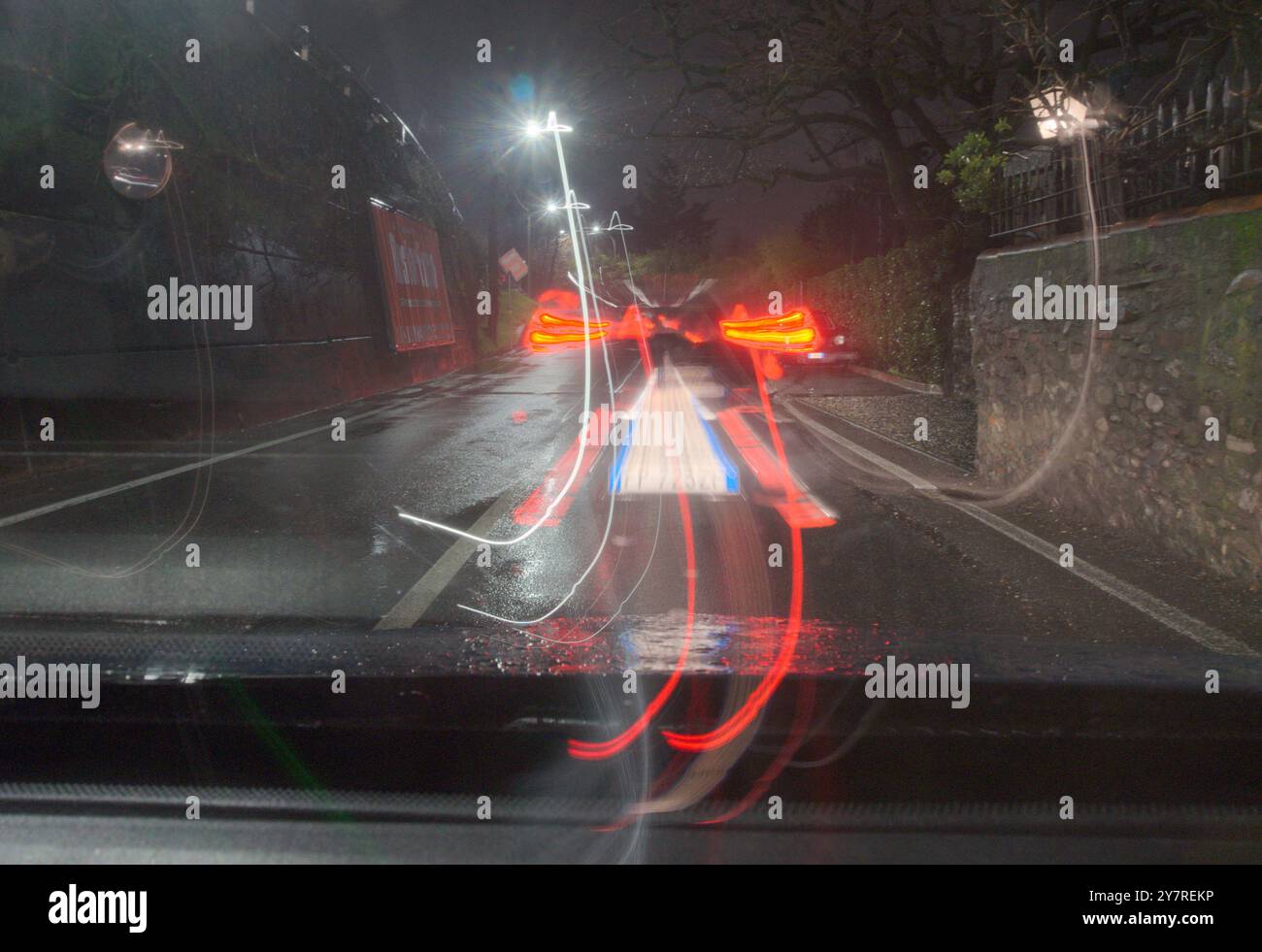 street scene at night through the windshield featuring a car with their ...