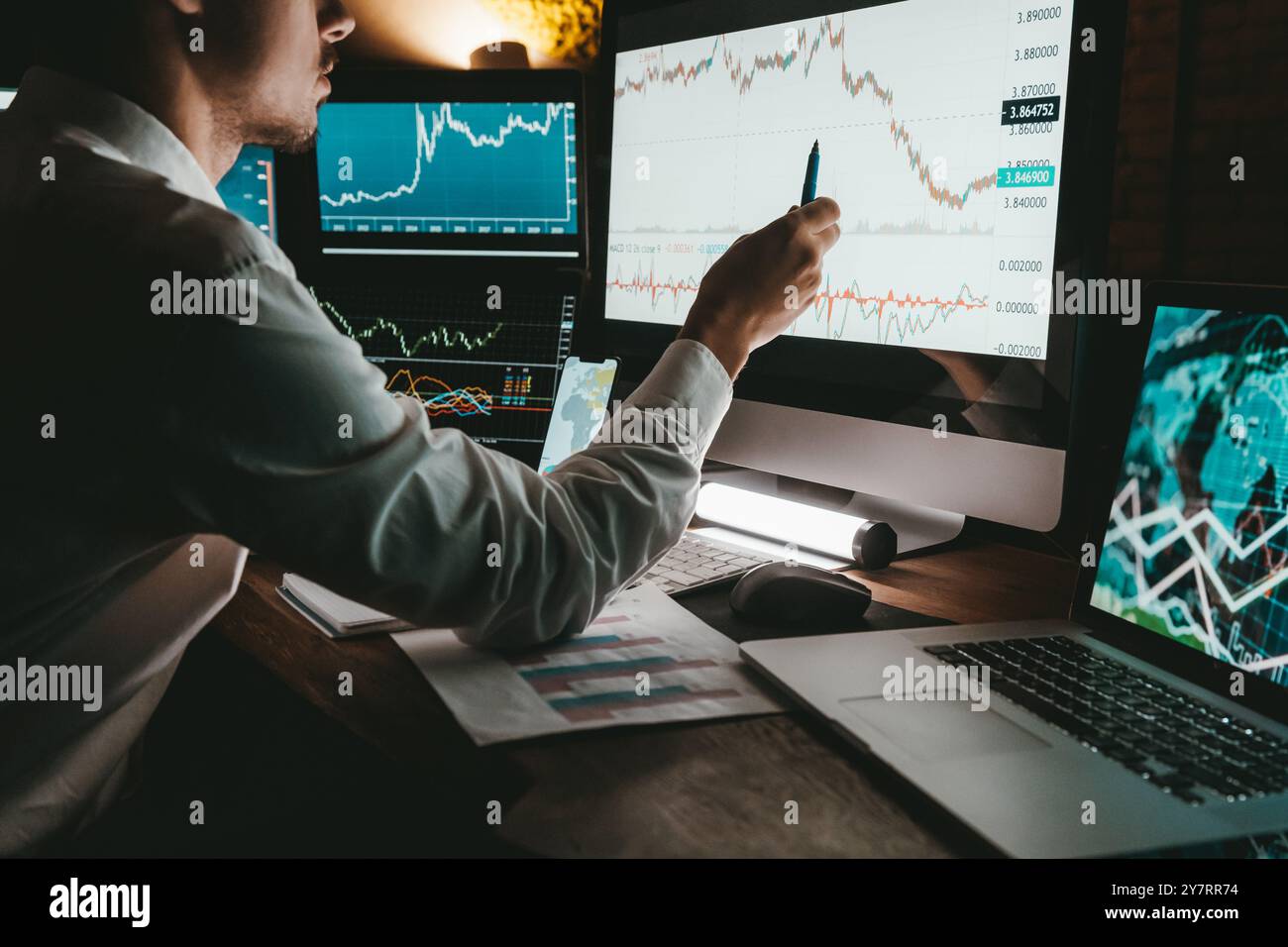 Close-up of male trader pointing computer monitor while analyzing stock market charts in night ...