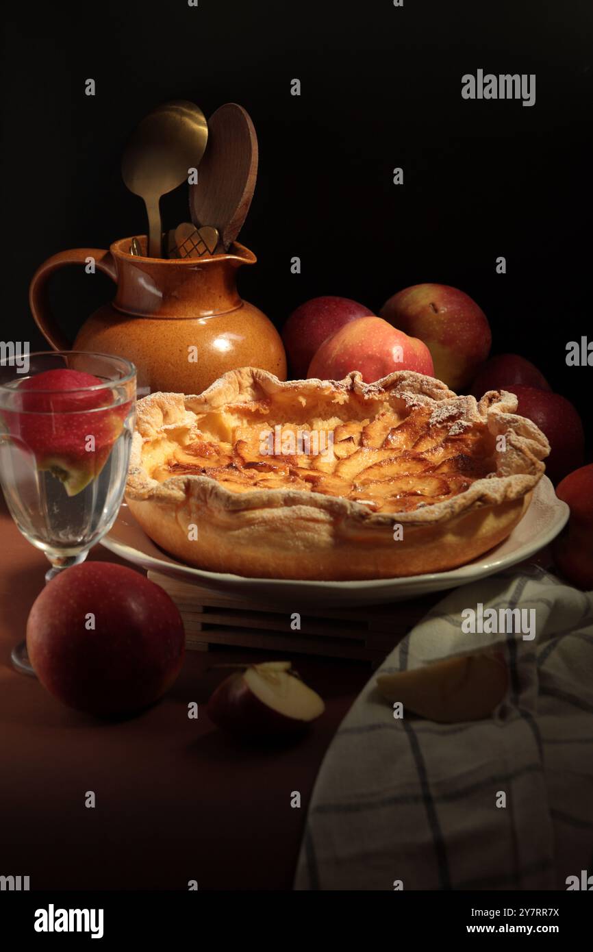 Rustic apple pie, fresh apples, and a ceramic jug with wooden spatulas ...