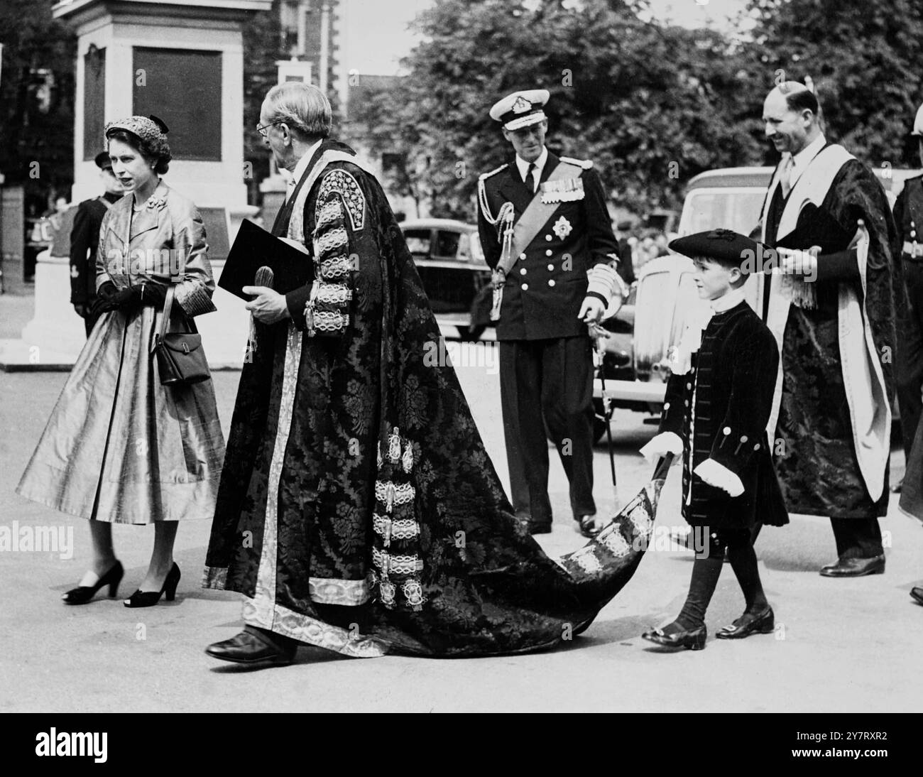QUEEN AND QUEEN'S UNIVERSITY Belfast, Northern Ireland : A young page-boy carries the train of ...