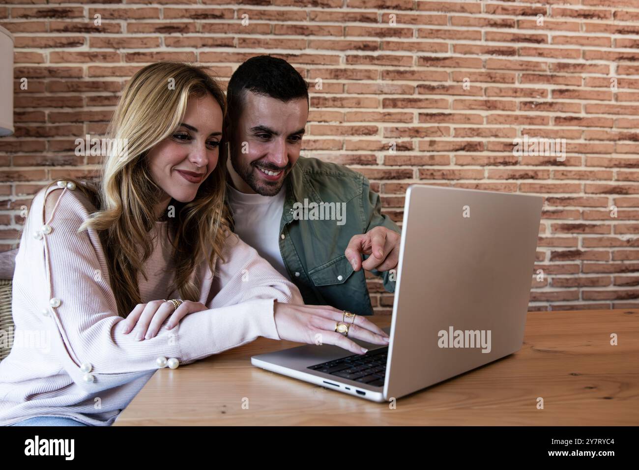 Young smiling couple connected on internet with laptop at their home ...