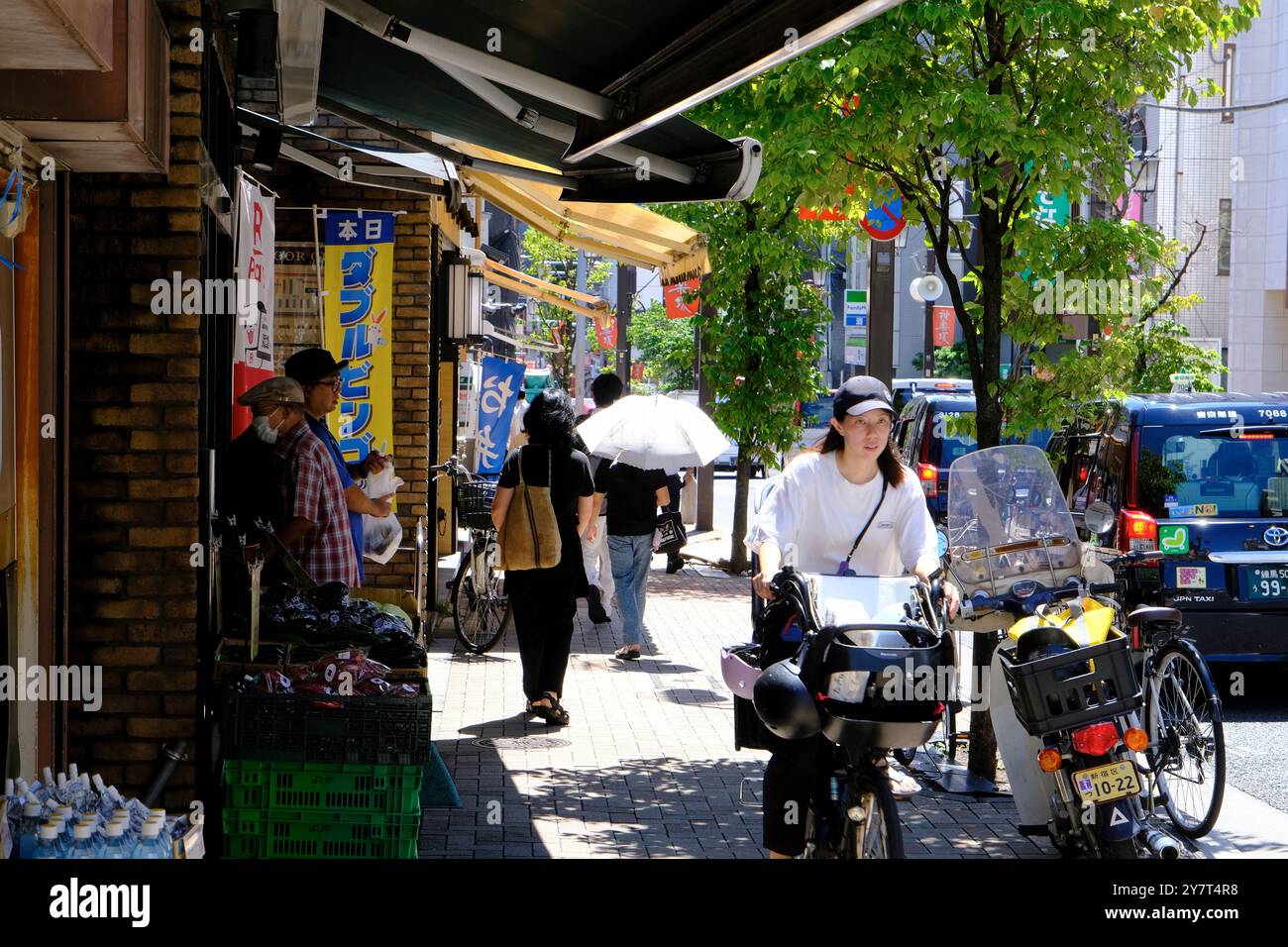 busy sidewalk with pedestrians and cyclist in Kagurazaka-dori,the main ...