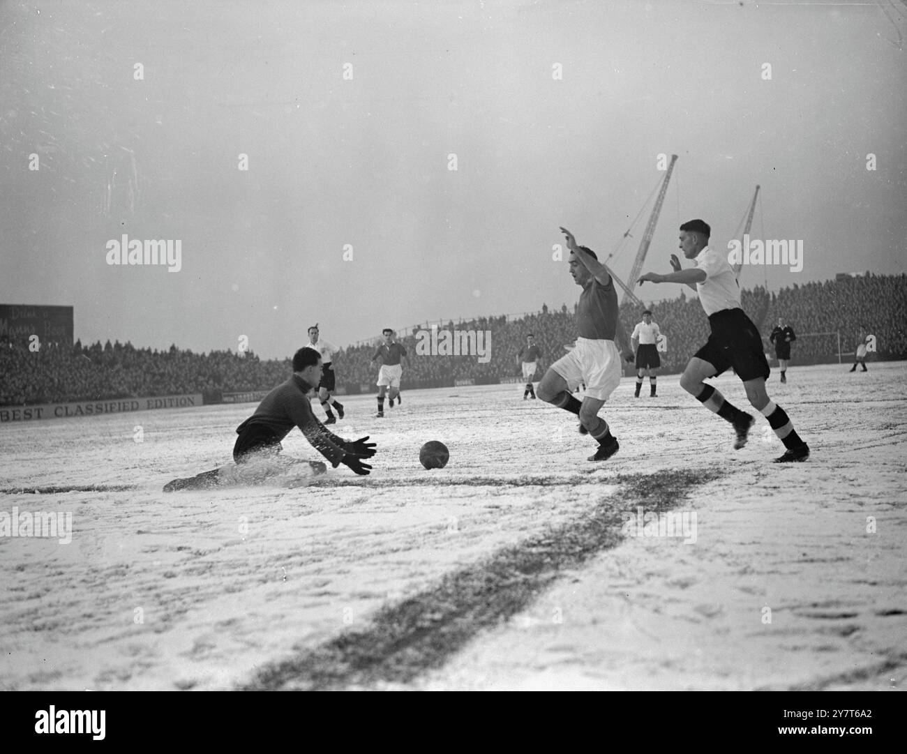 FOOTBALL STUDY- IN BLACK AND WHITE Sliding to his knees in the snow ...