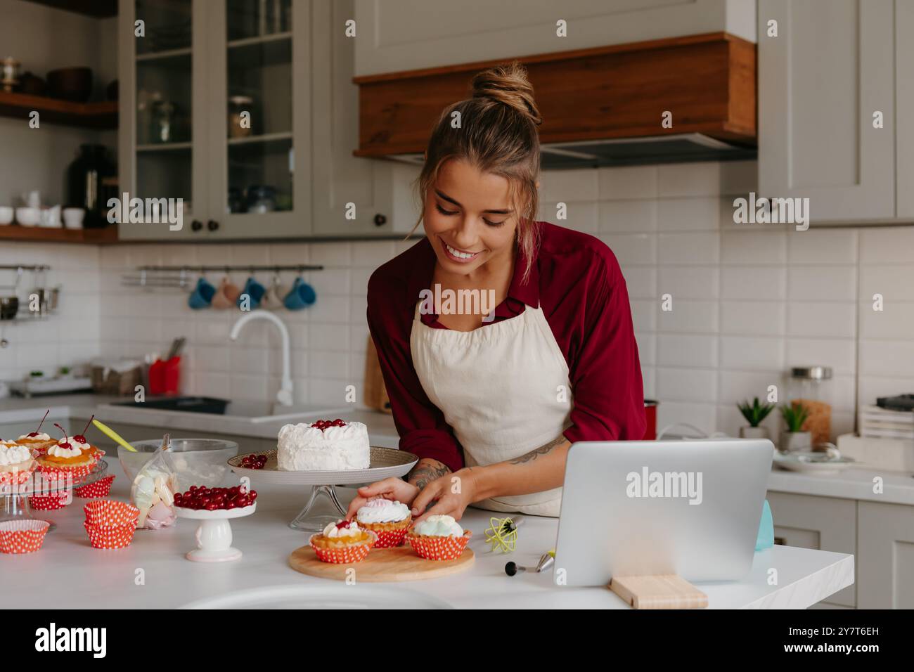 Beautiful female baker merchandising muffins and smiling while standing ...