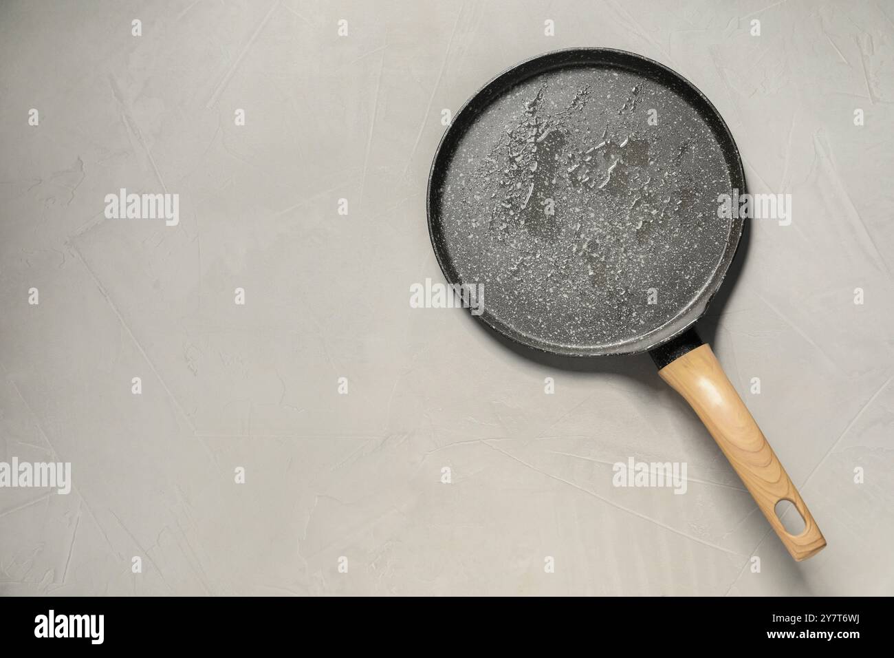 Frying pan with oil on gray textured table, top view. Space for text ...