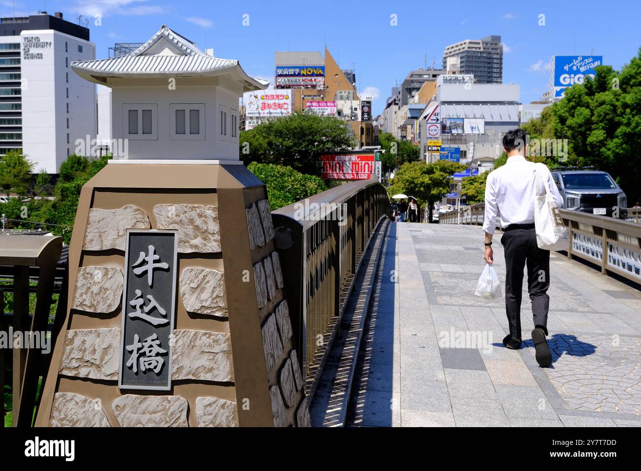 Pedestrians walking on Ushigome Bridge with it's Kanji name plaque on ...