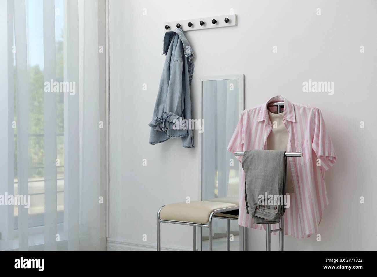Coat rack, stool, mirror and clothes in hallway Stock Photo - Alamy