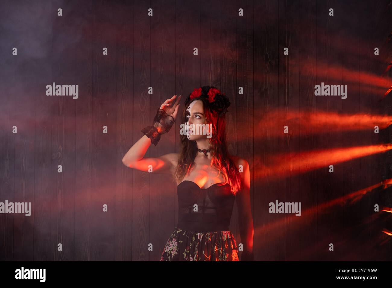 Woman wearing sugar skull makeup stands in dramatic red lighting ...