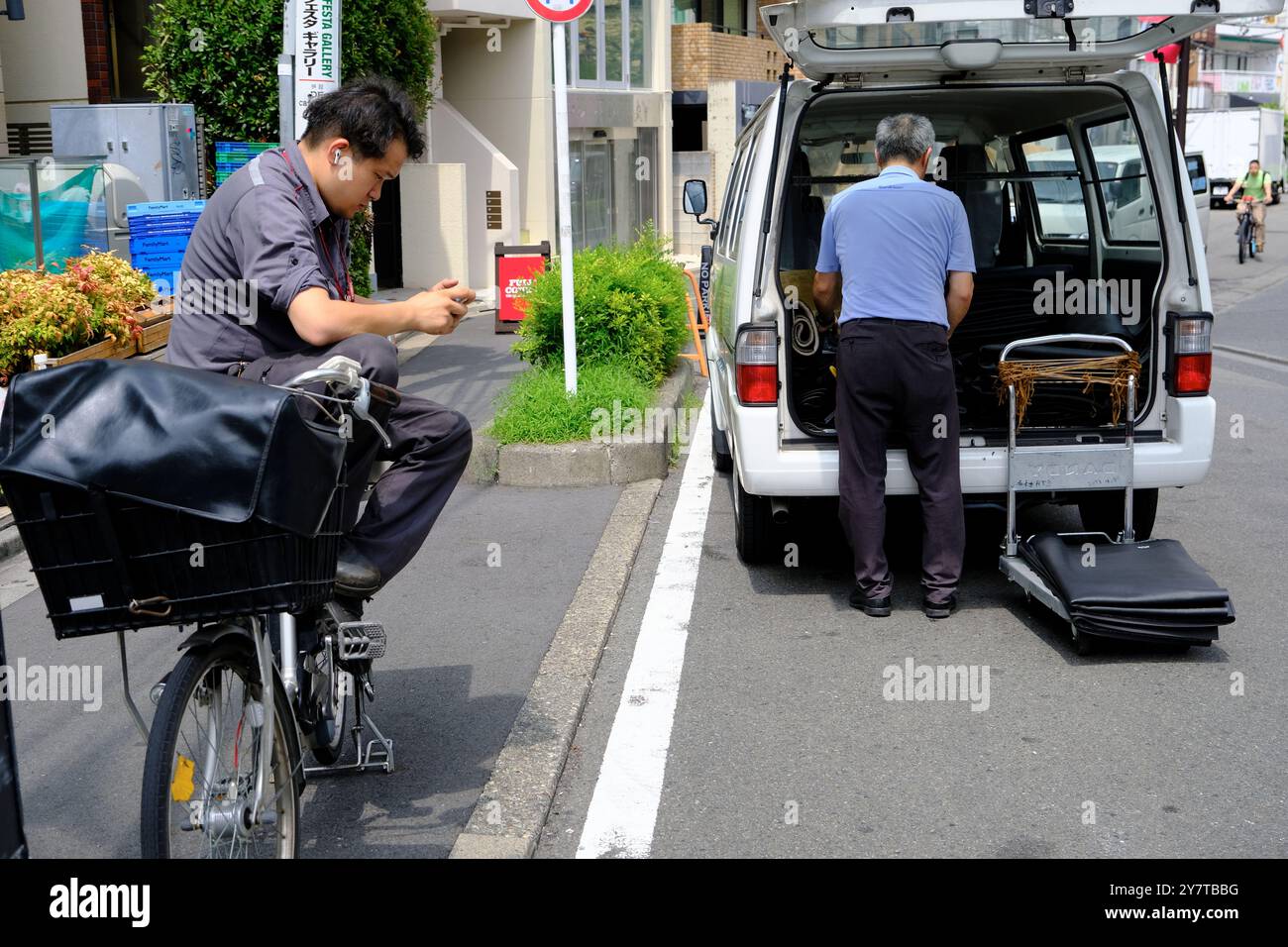 A bicycle messenger sitting on his bicycle and looking at his phone ...