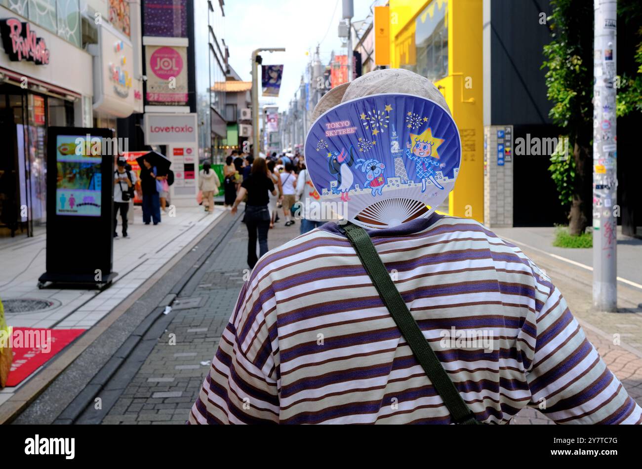 A man put a his fan on the back of neck.Takeshita Dori street. Harajuku ...