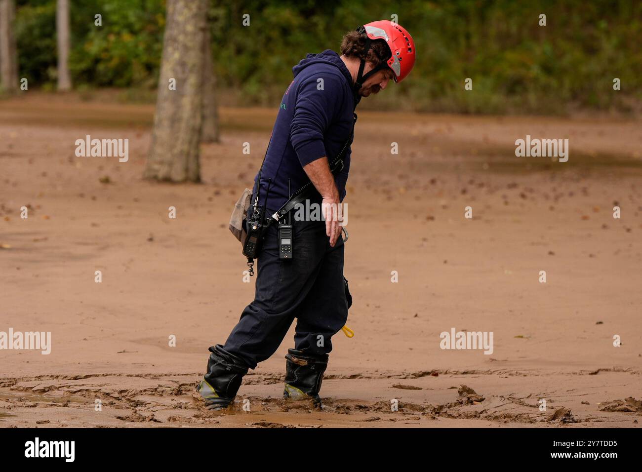 A fireman walks through mud as they search for victims of flash ...